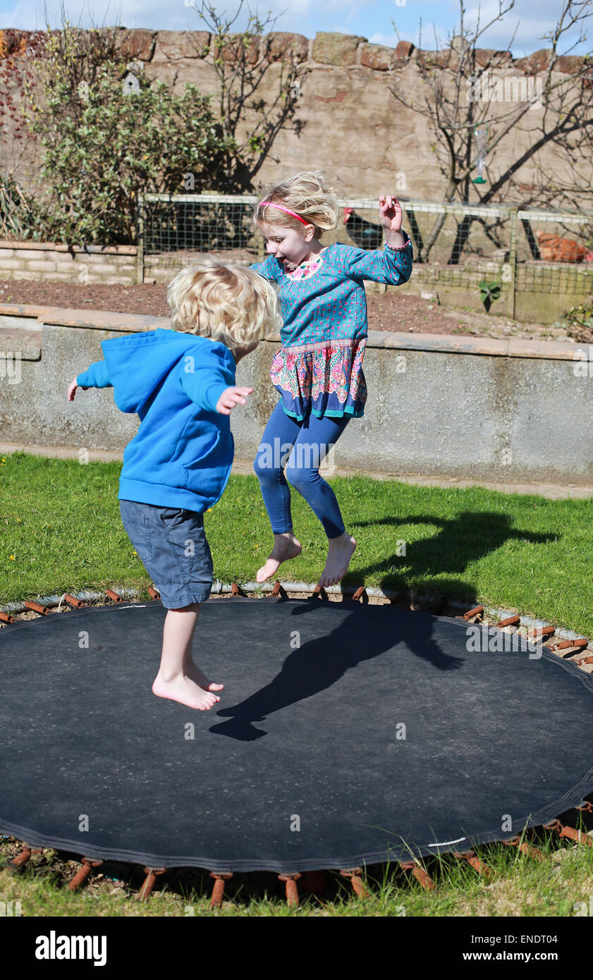 Brother and sister jumping on a trampoline Stock Photo - Alamy