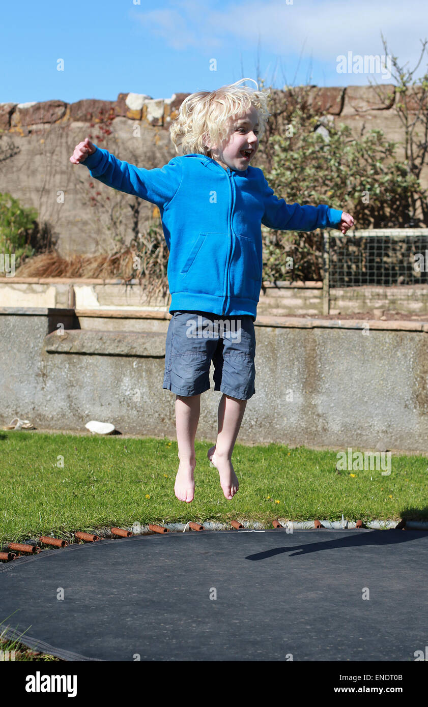 Little boy jumping on a trampoline in the garden Stock Photo - Alamy