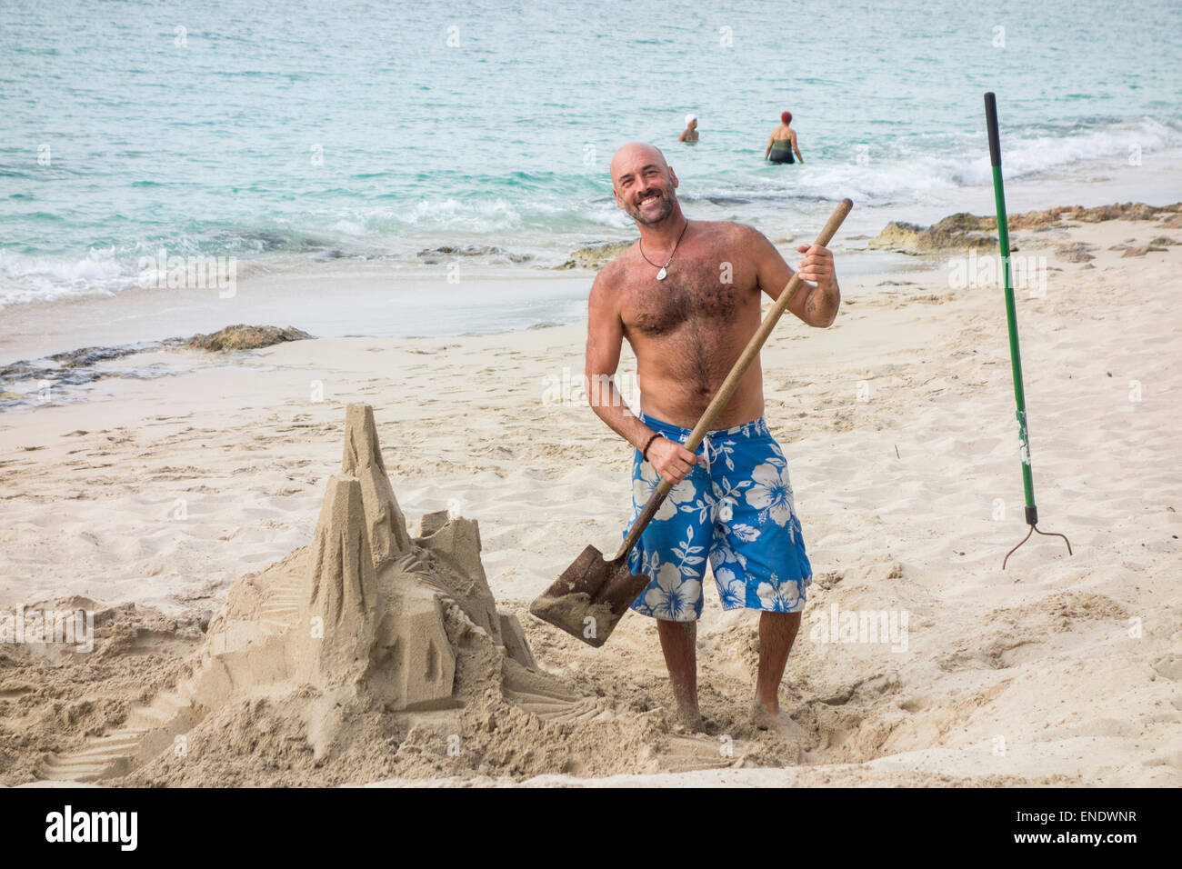 A Caucasian man smiles while building a sand castle on Sandcastle Beach ...