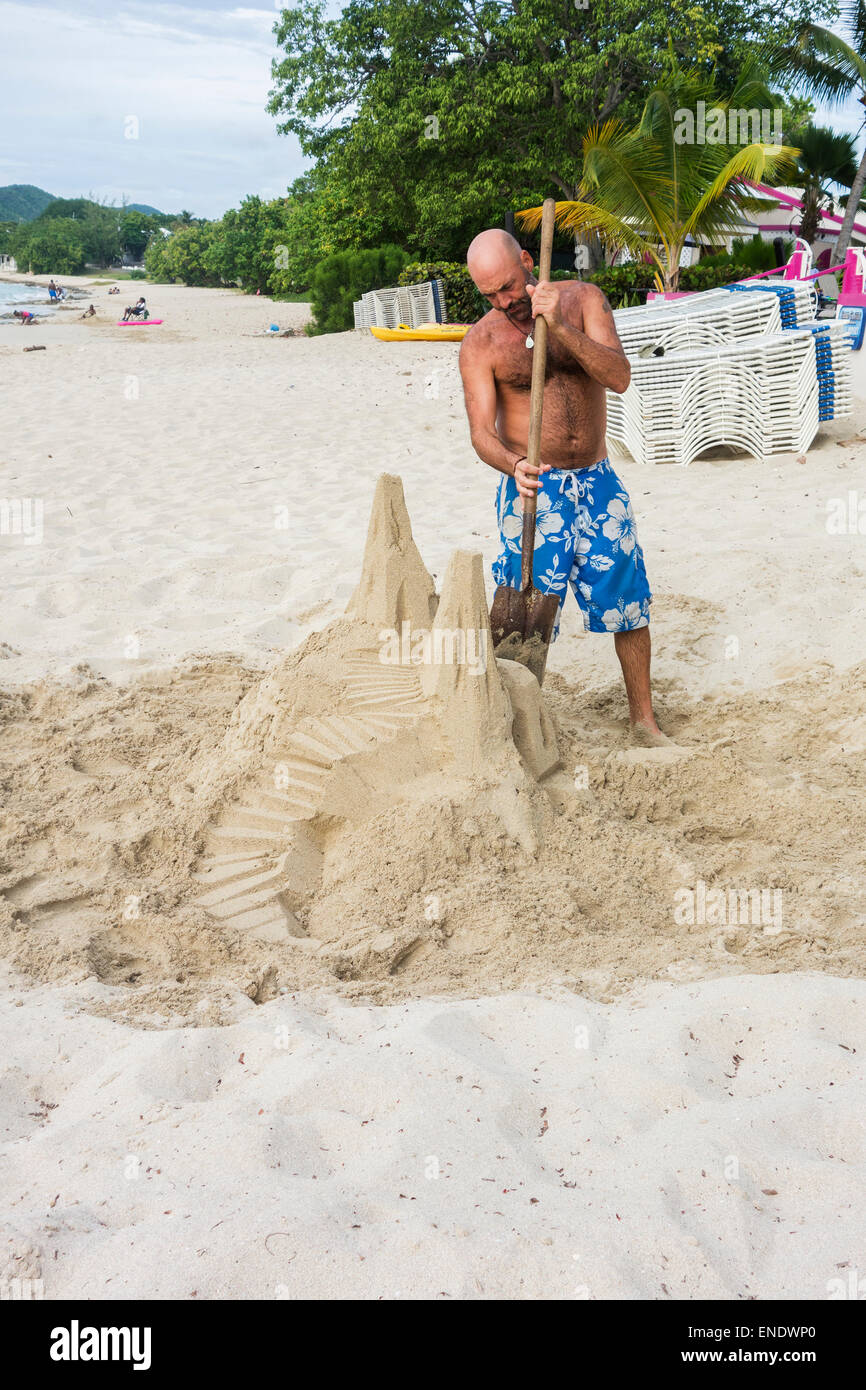 A Caucasian man builds a sand castle on Sandcastle Beach, west end, St ...