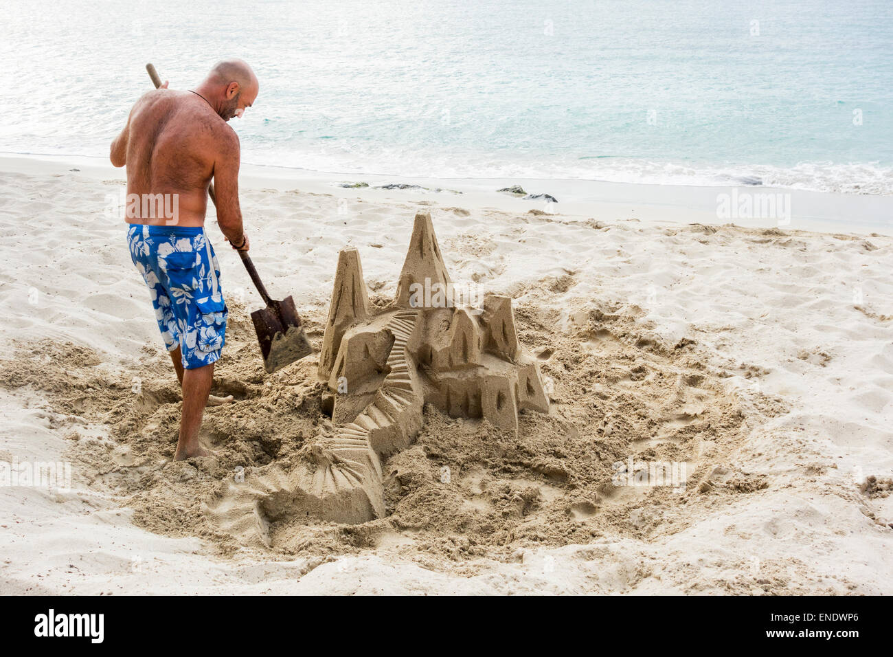 A Caucasian man builds a sand castle on Sandcastle Beach, west end, St ...
