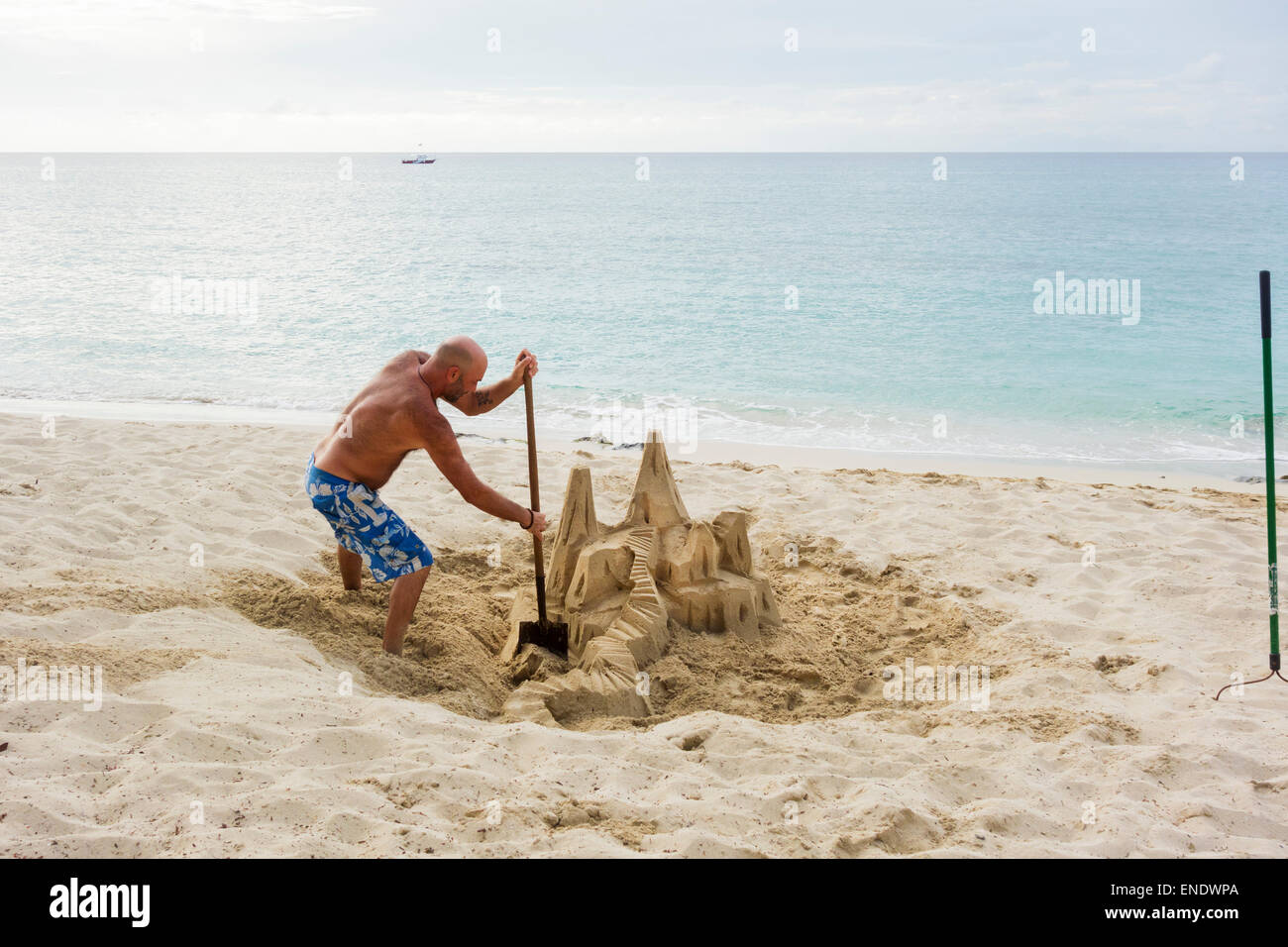 A Caucasian man builds a sand castle on Sandcastle Beach, west end, St ...