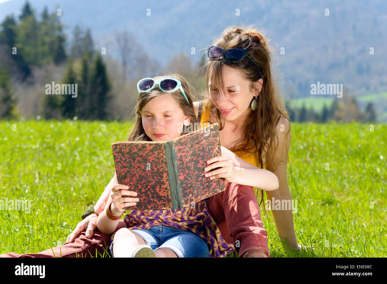 Mom and daughter reading a book in nature Stock Photo - Alamy