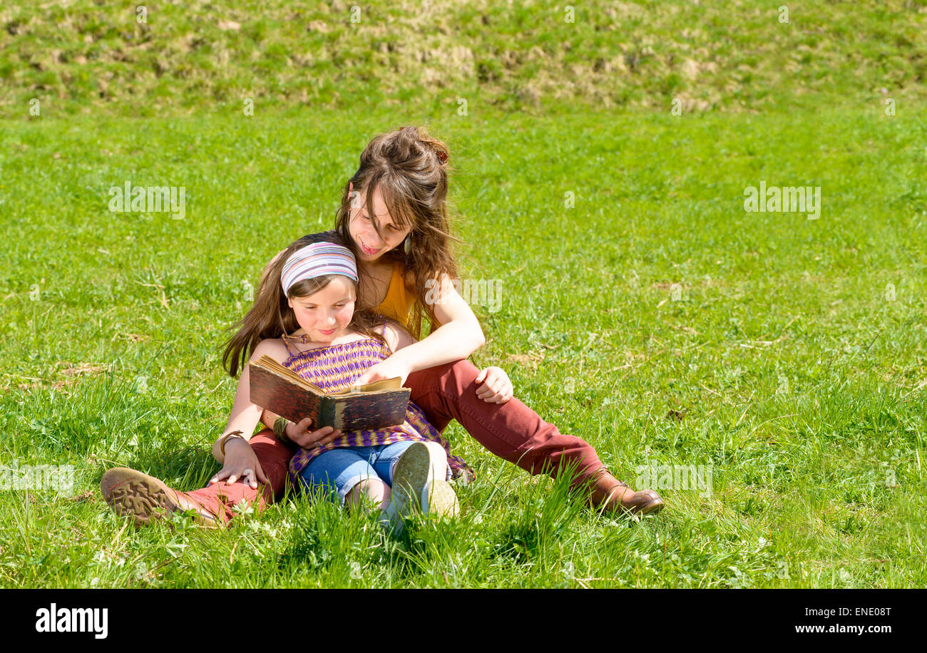 Mom and daughter reading a book in nature Stock Photo - Alamy