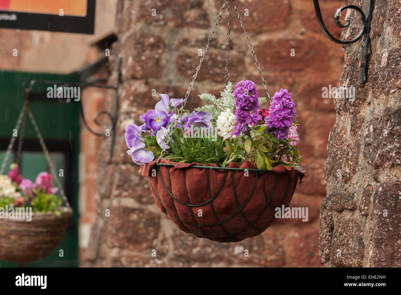 Hanging baskets in front of a stone wall Stock Photo - Alamy