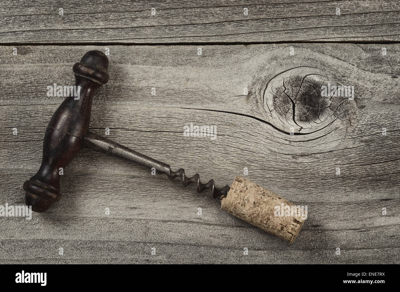 Vintage concept of an old corkscrew with attached cork on rustic wooden ...