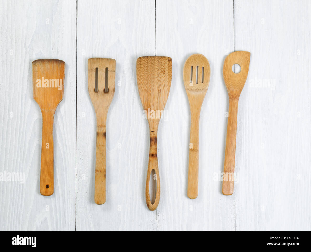 Overhead angled shot of wooden spatula, spoons on white wood. Format in ...