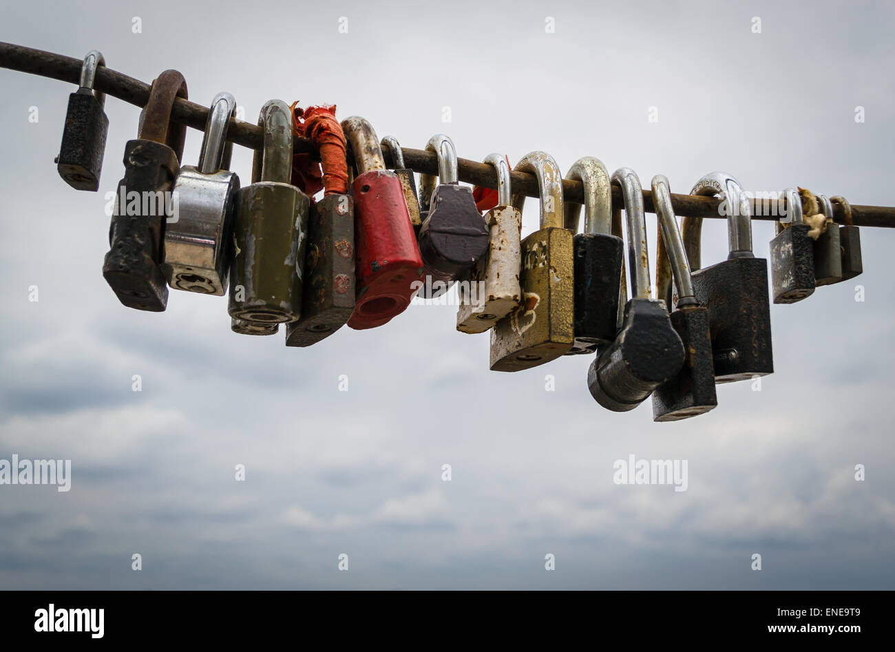 Various locked steel padlocks on a secure tough iron rod against a ...