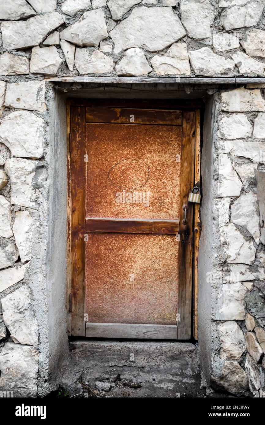 A padlocked wooden door surrounded by grey rock and cement Stock Photo ...