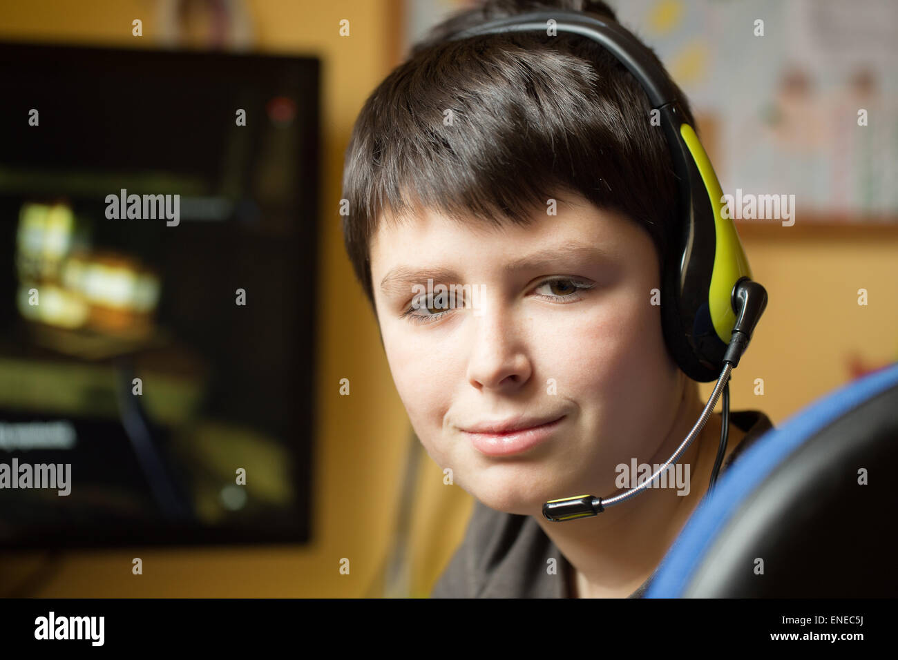 Teenager using computer at home with headphones, play game in his child ...