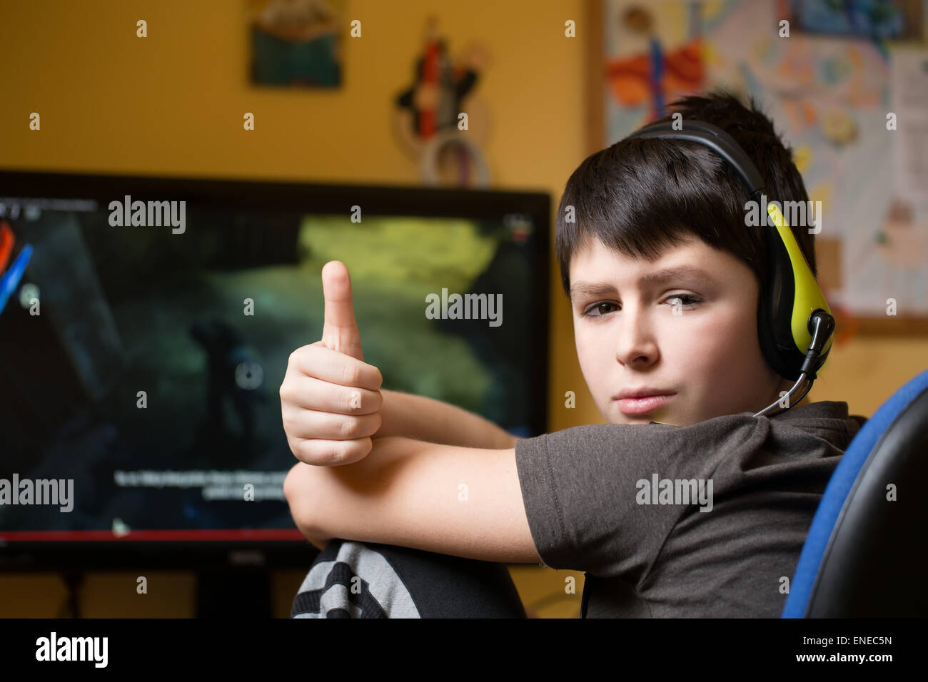 Teenager using computer at home with headphones, play game in his child ...