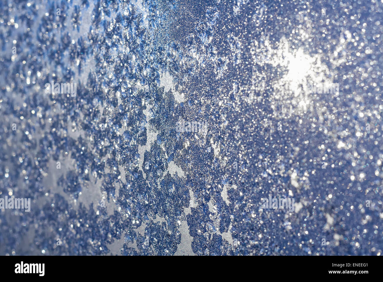 Ice and frost background over the sun on frozen window. Colored in blue ...