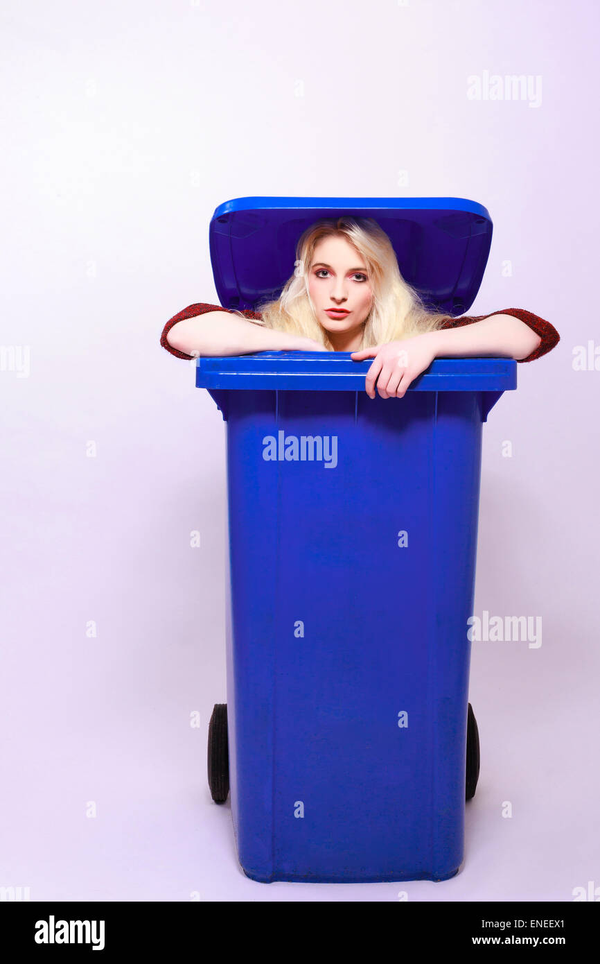 Young woman kneeling in a garbage can Stock Photo - Alamy
