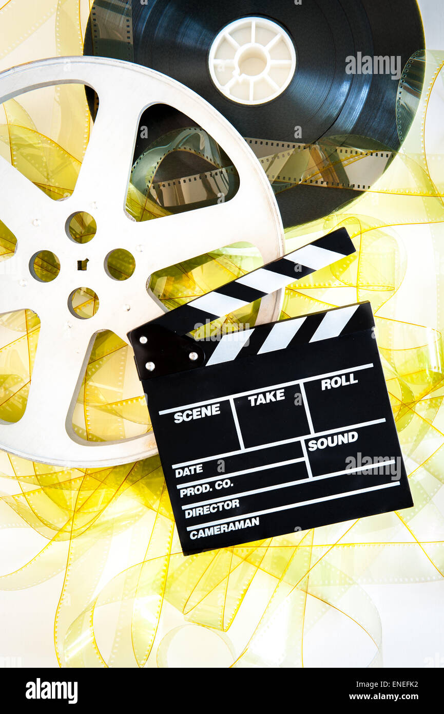 Movie clapper on 35 mm cinema reels unrolled yellow filmstrip on white ...