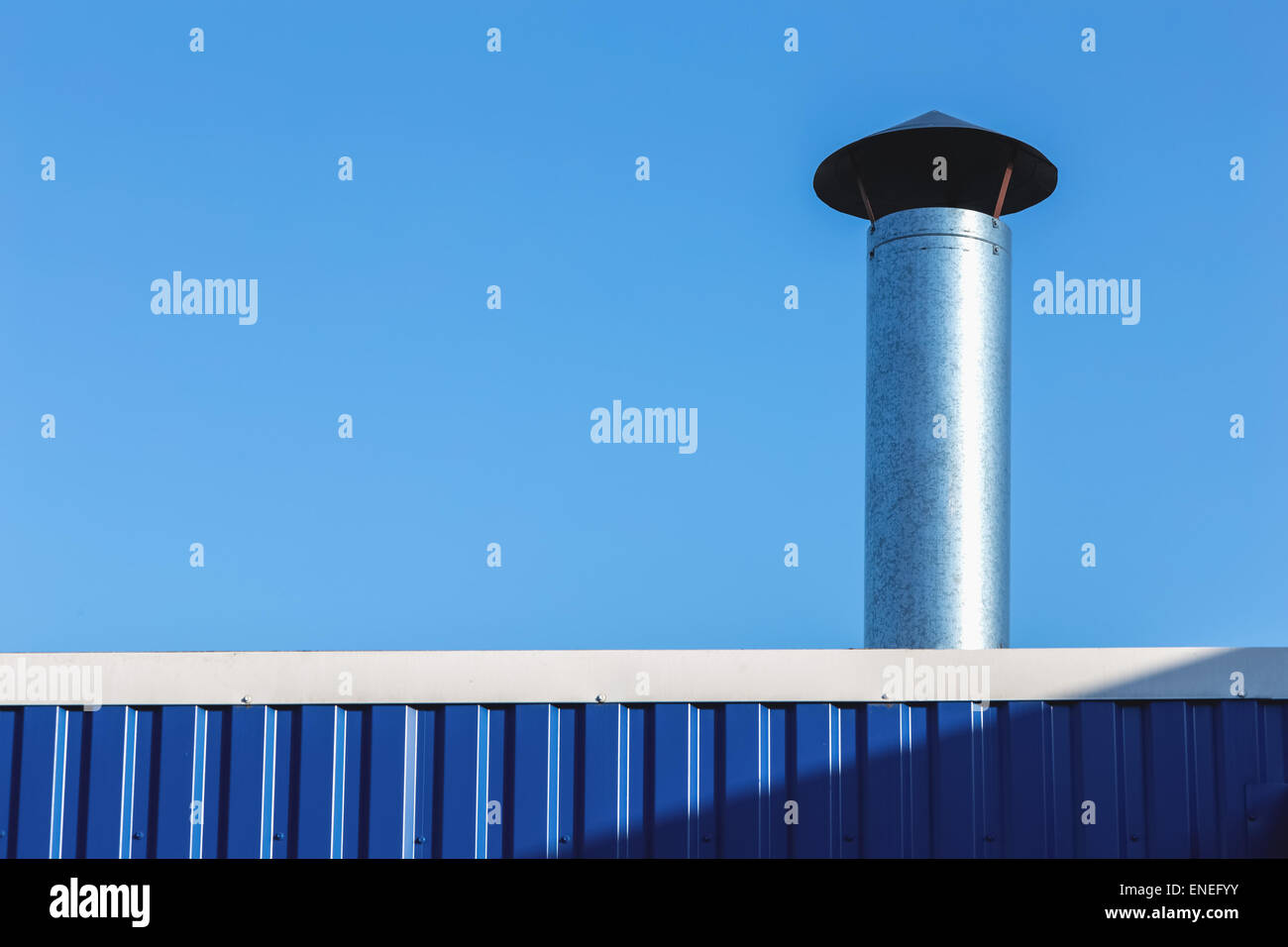 Metal chimney on building rooftop on blue sky background Stock Photo ...