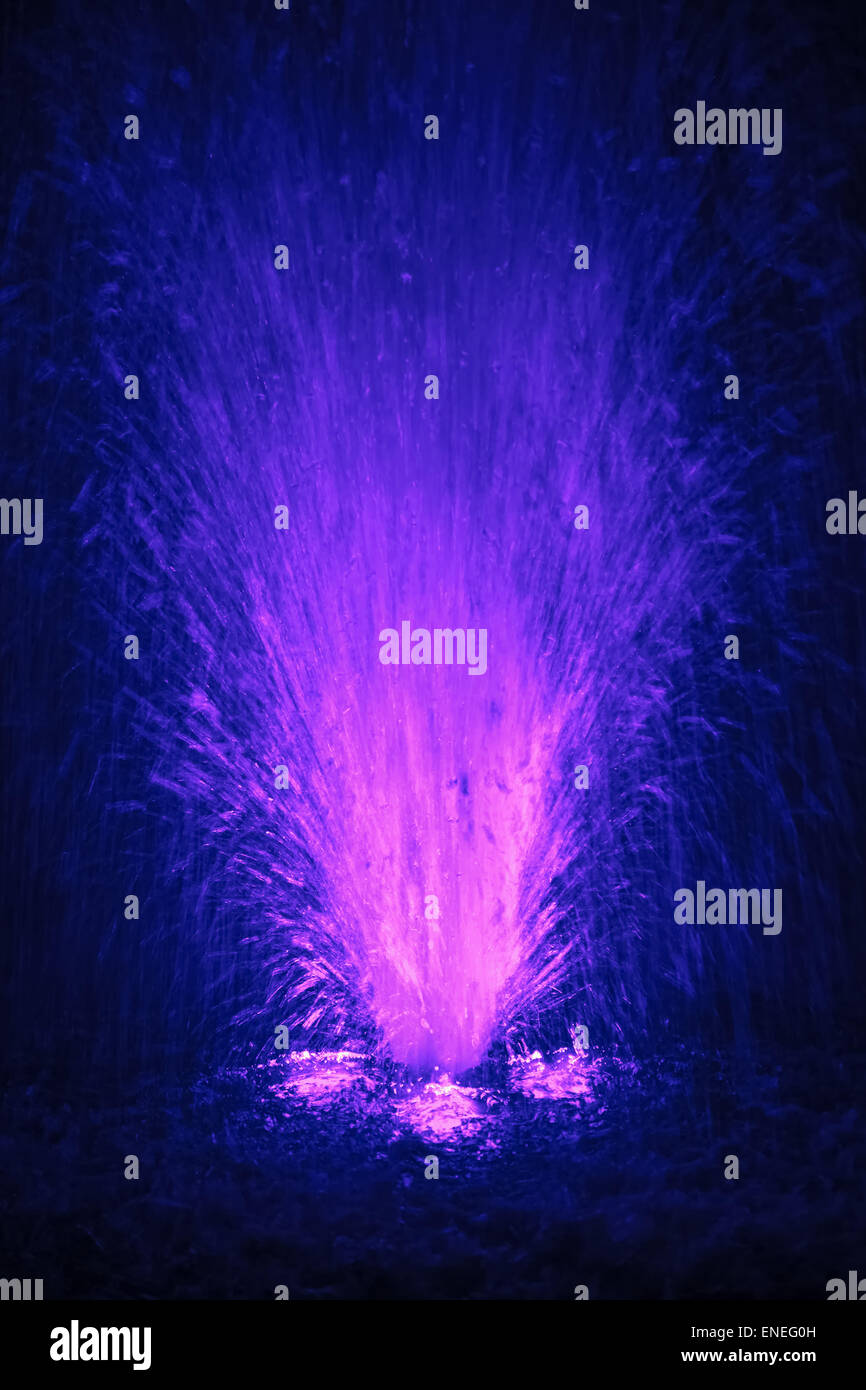 Colorful fountain splashes violet and blue color of water drops on a ...