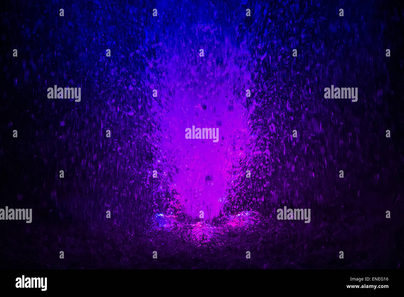 Colorful fountain splashes violet and blue color of water drops on a ...