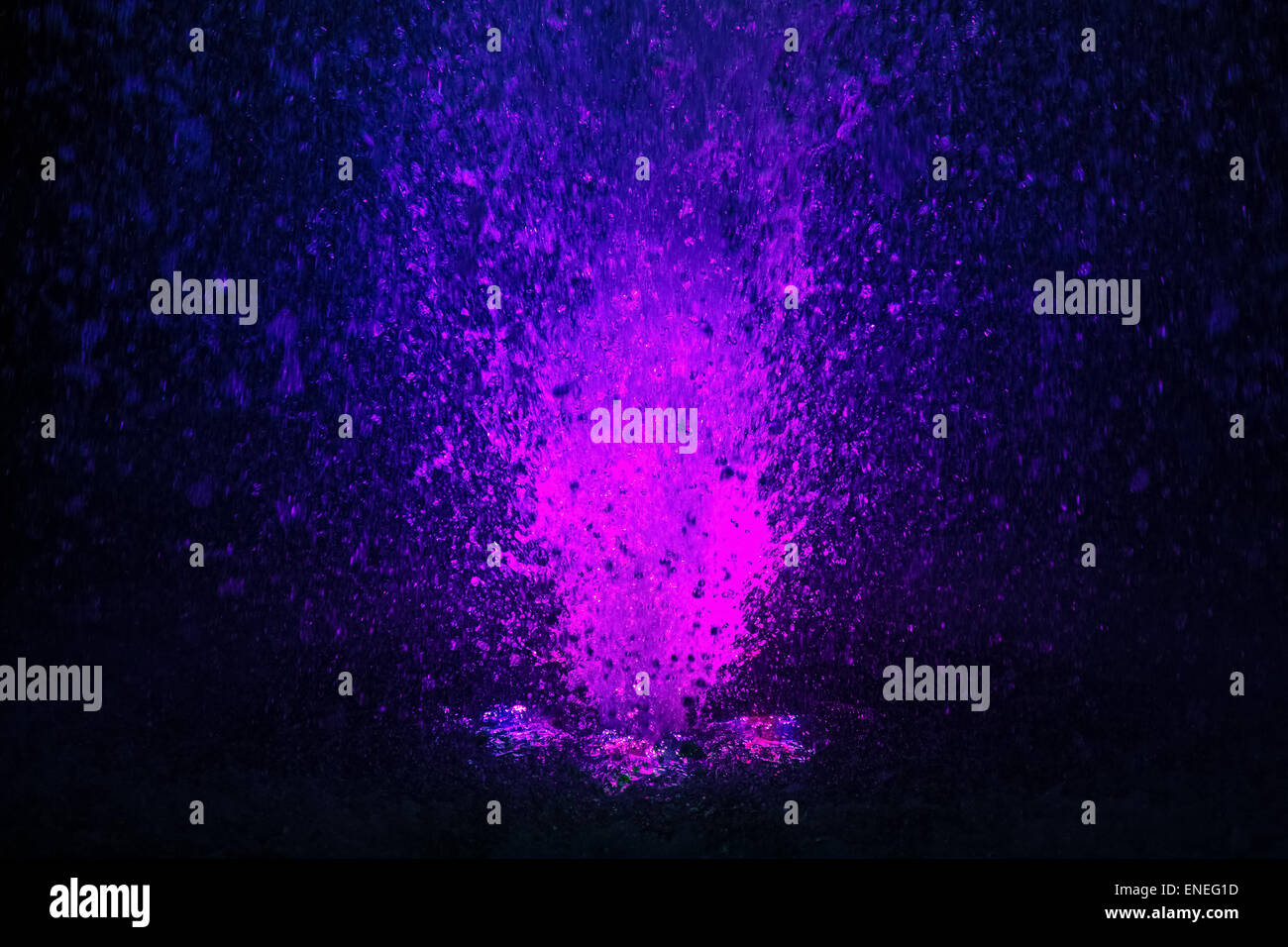 Colorful fountain splashes violet and blue color of water drops on a ...