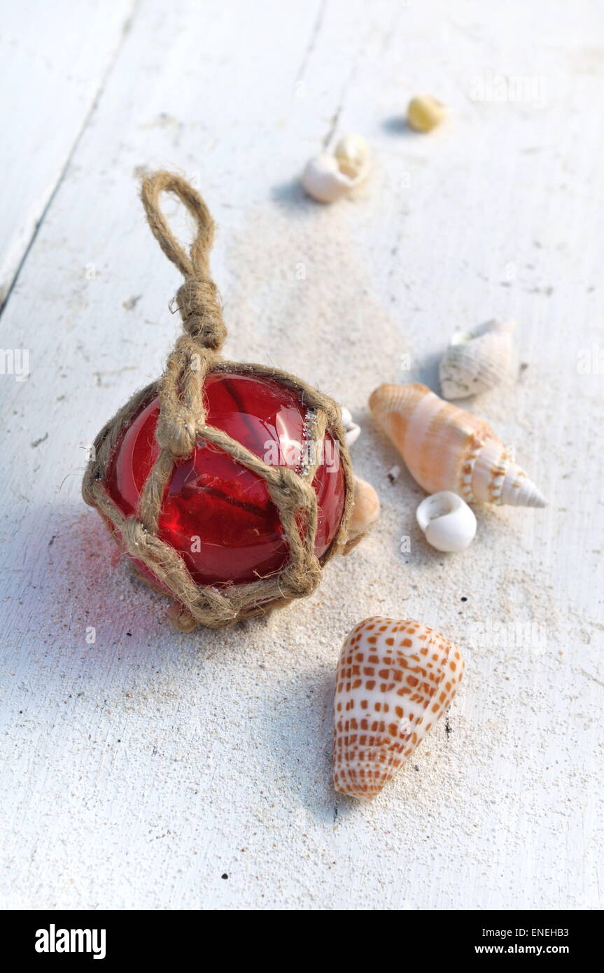 small red float among seashells and sea on a white plank Stock Photo ...