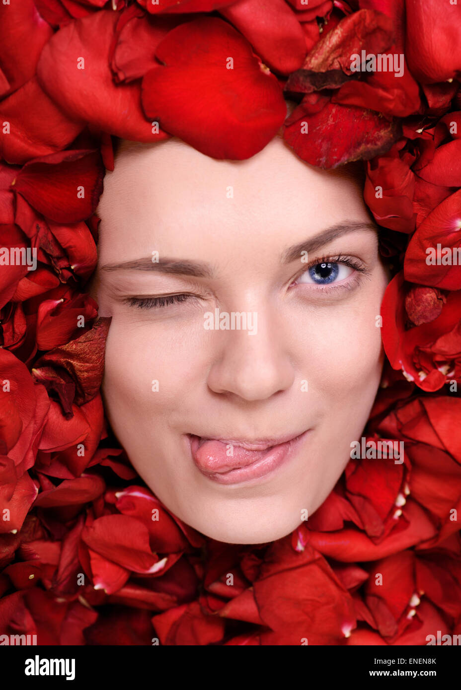 Cheerful woman show tongue. Lie in petal of roses. Top view Stock Photo ...