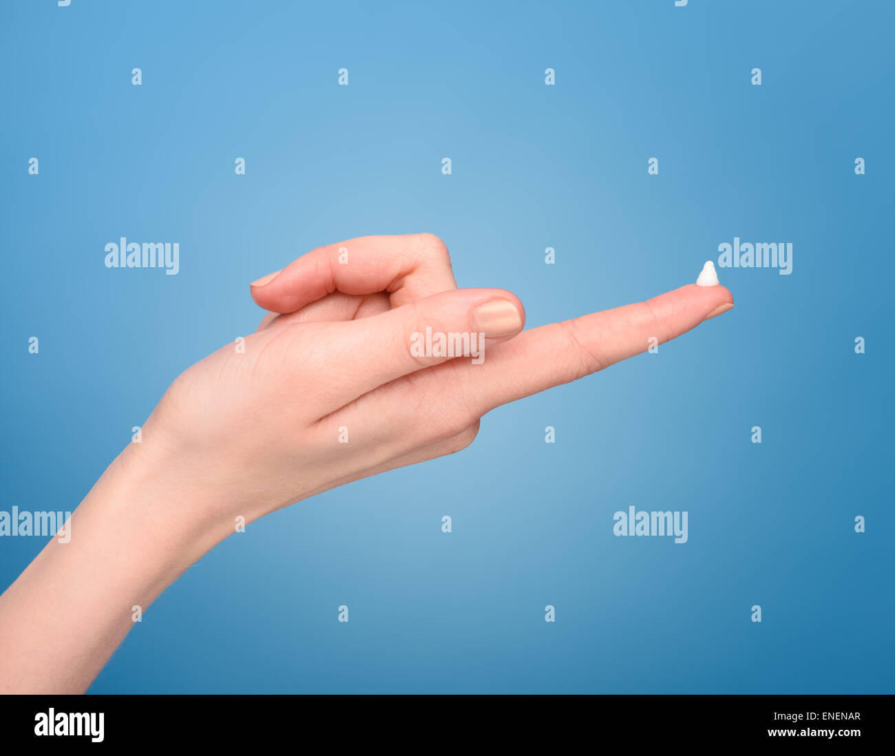 Moisturizing hand cream on woman finger. Blue background high ...