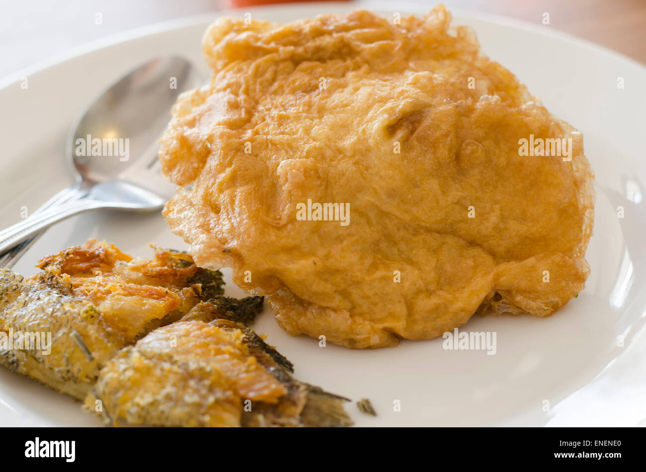 fried fish and omelet in dish with spoon and fork Stock Photo - Alamy