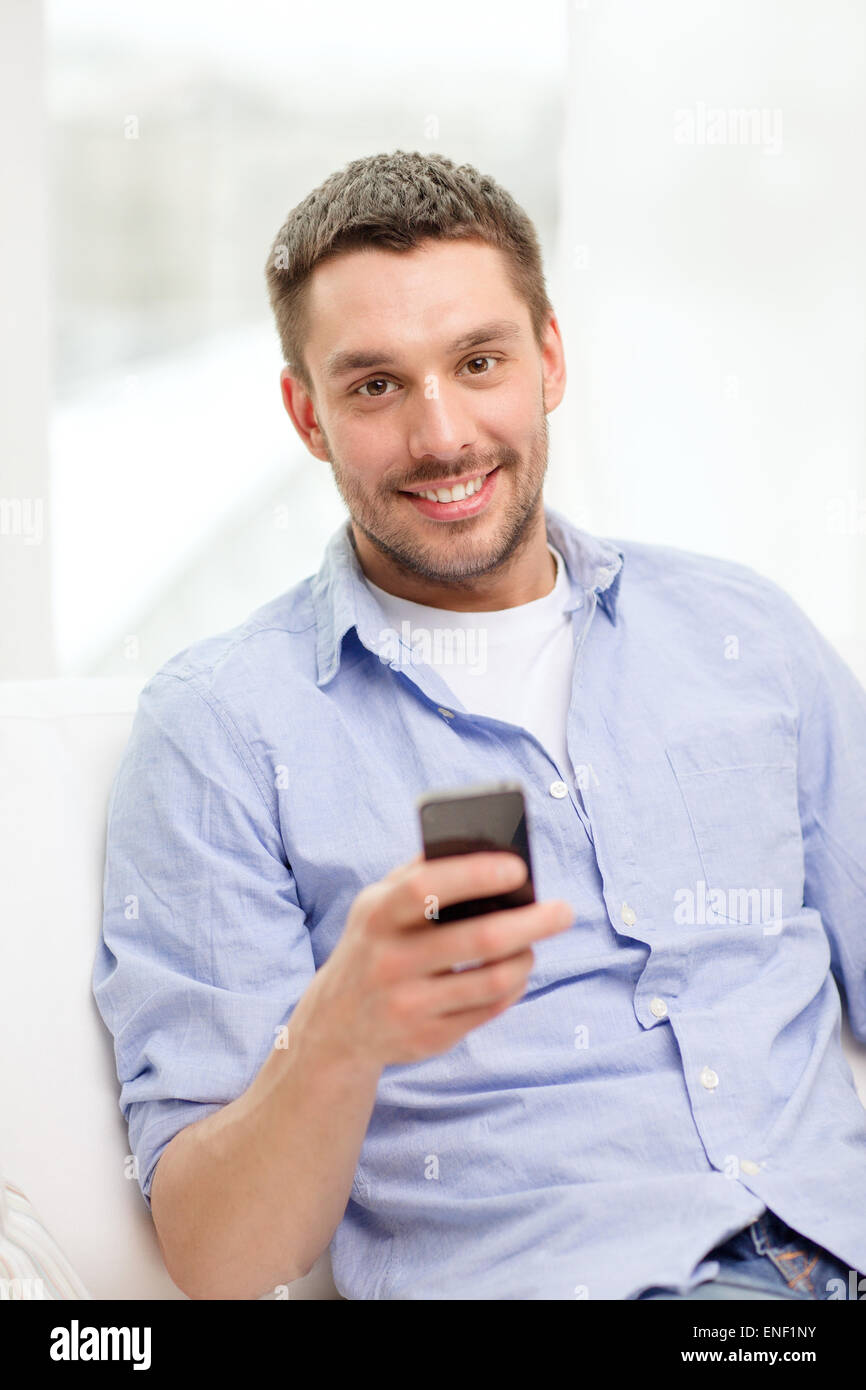 smiling man with smartphone at home Stock Photo - Alamy