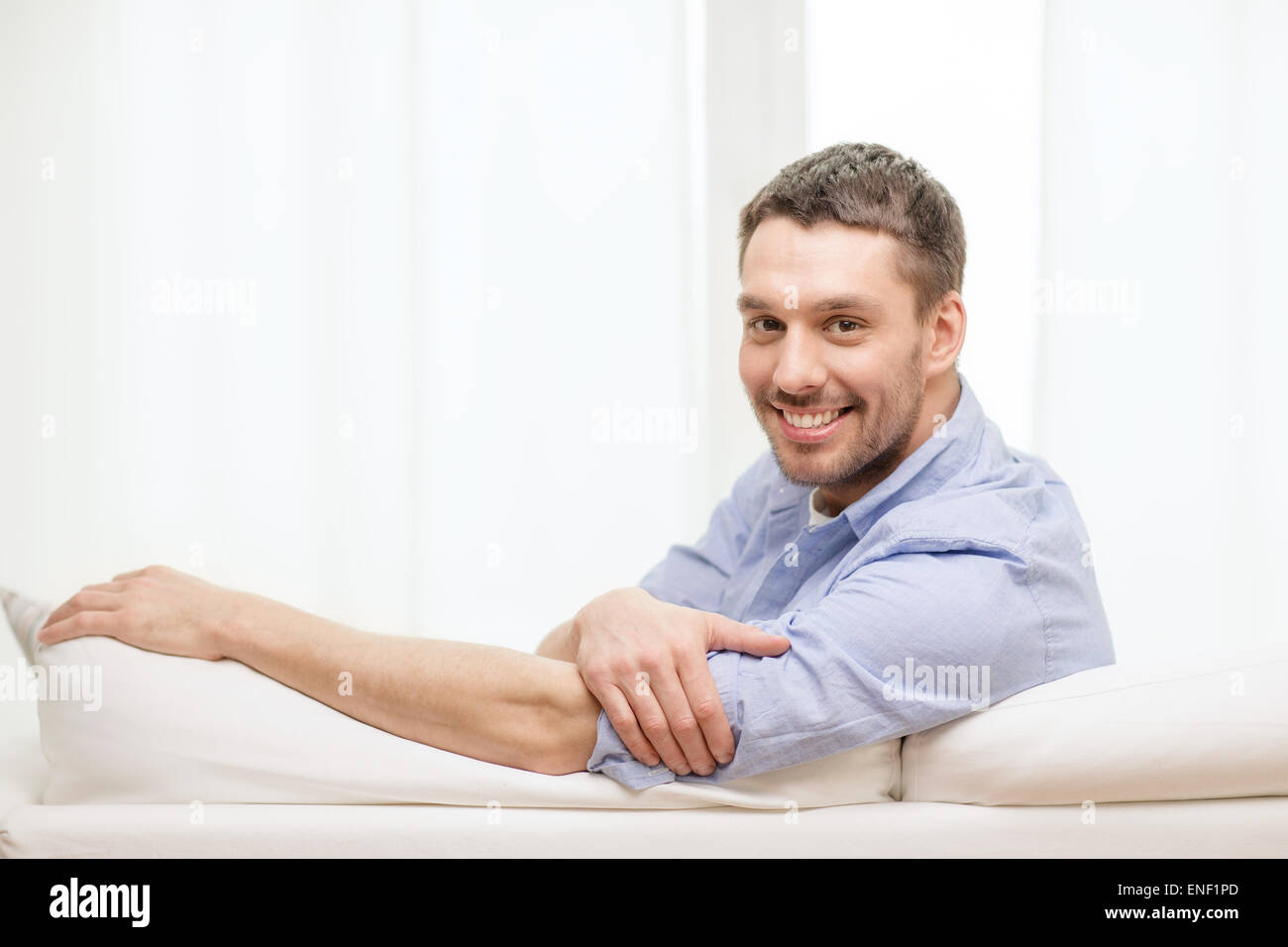 smiling man sitting on sofa at home Stock Photo - Alamy