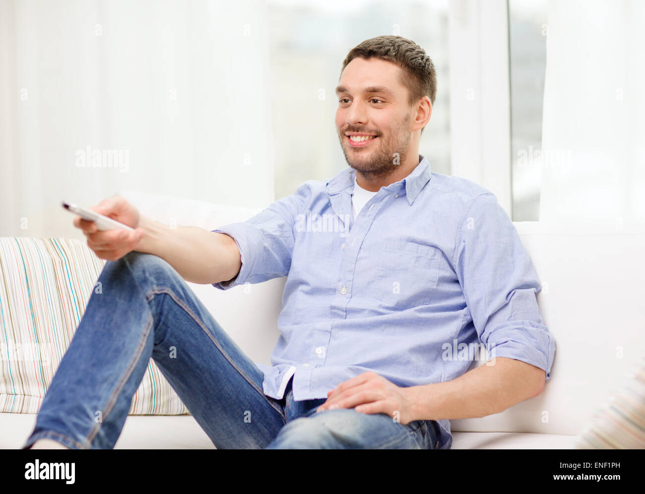 smiling man with tv remote control at home Stock Photo - Alamy