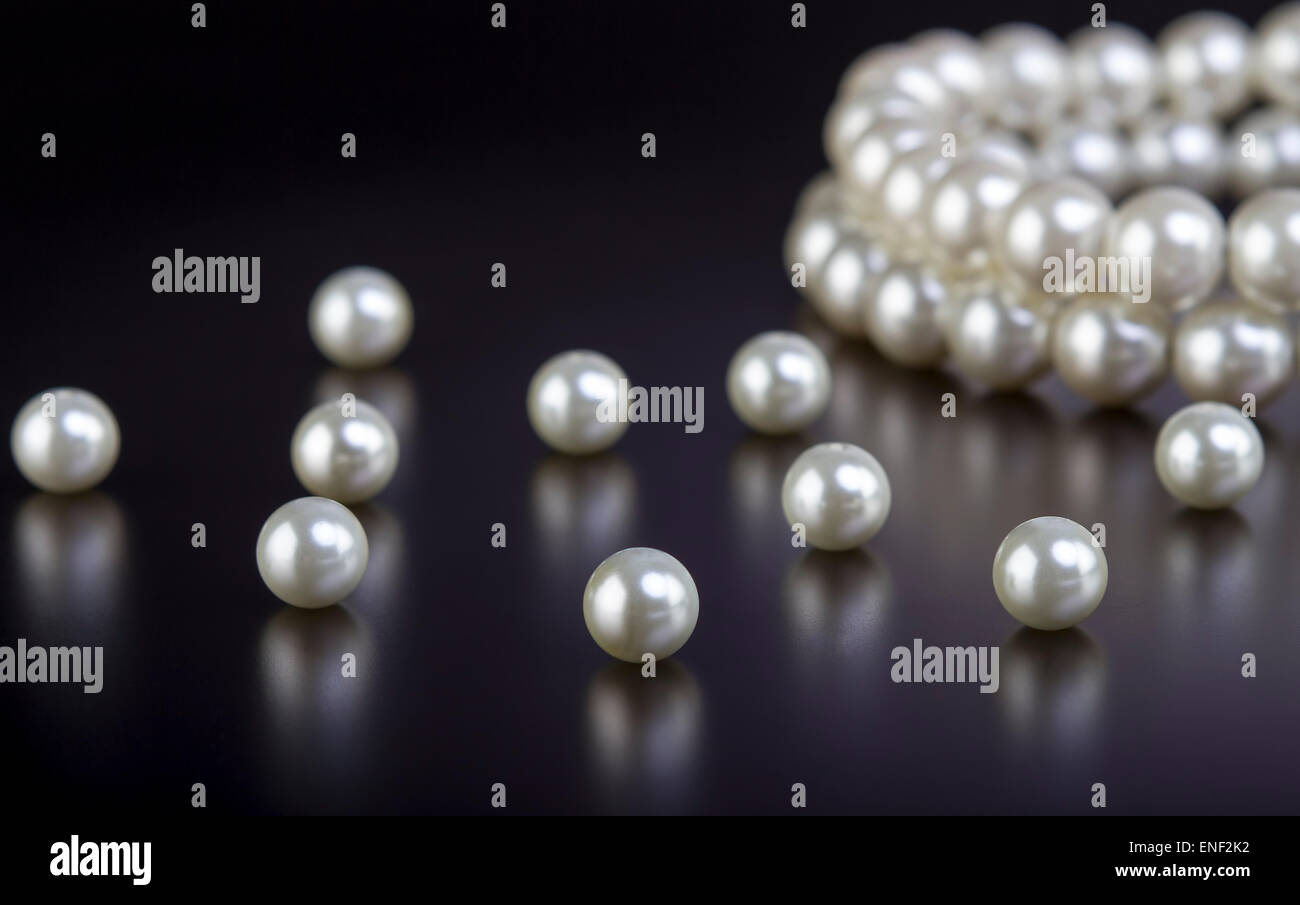 White pearls necklace on black background Stock Photo - Alamy