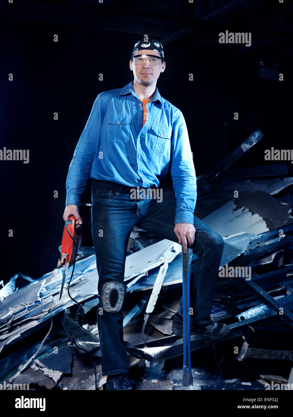 Portrait of a man with a sledgehammer and a saw doing renovations and ...
