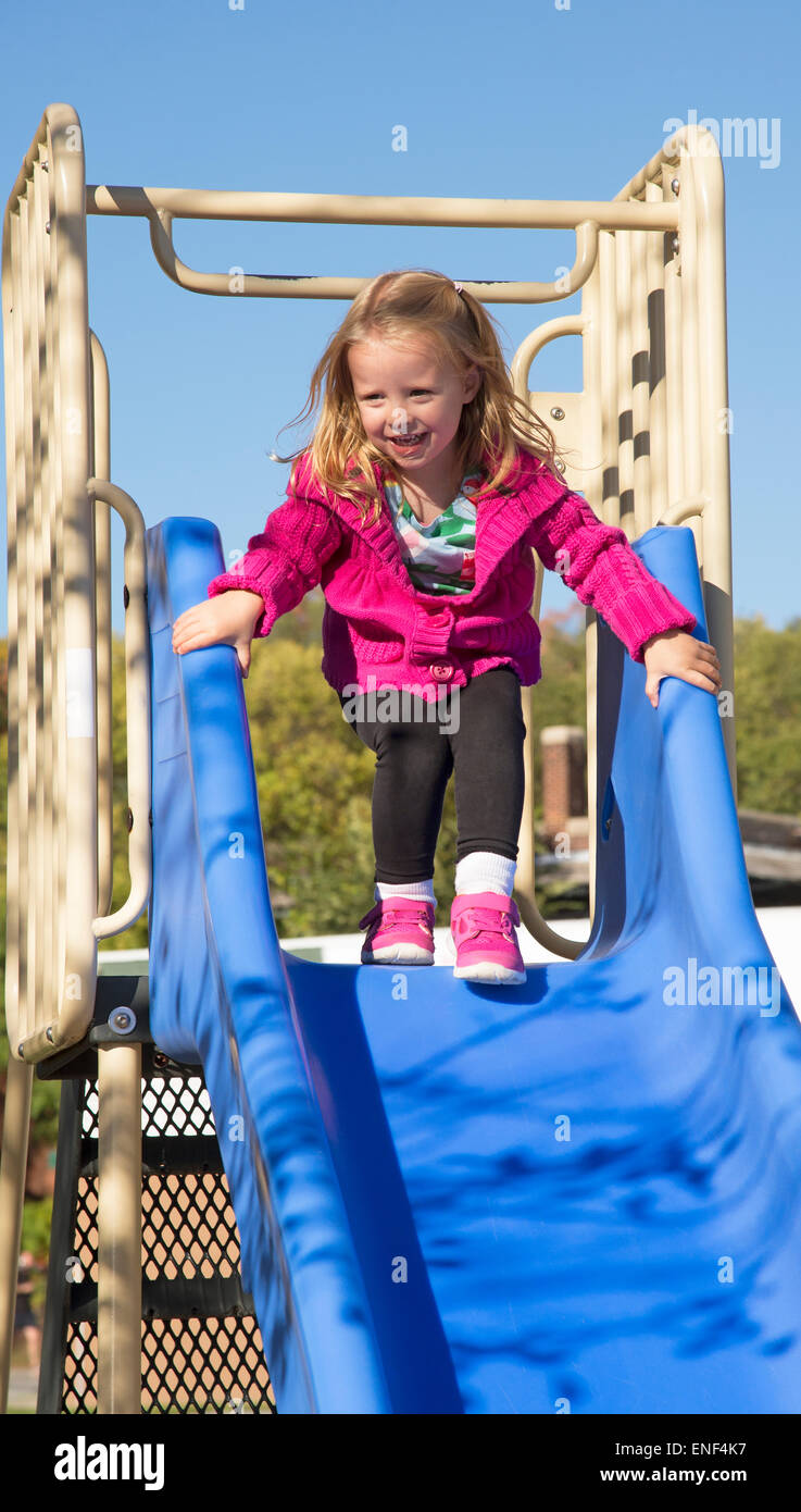 Little girl playing on a blue slide in a playground Stock Photo - Alamy