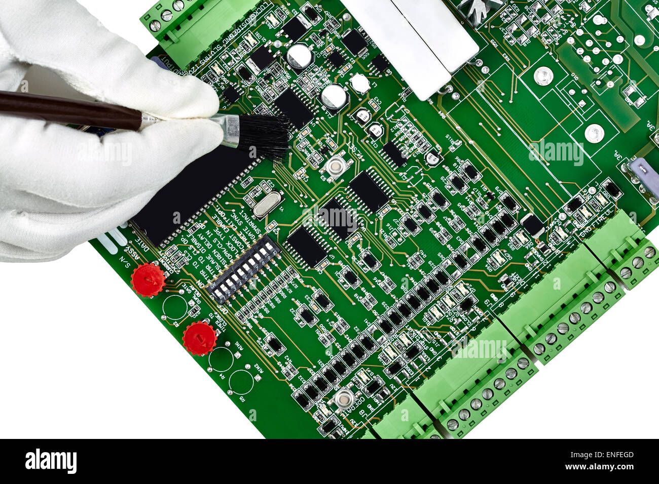 Circuit board with hand in white glove holding brush cleaning the board ...