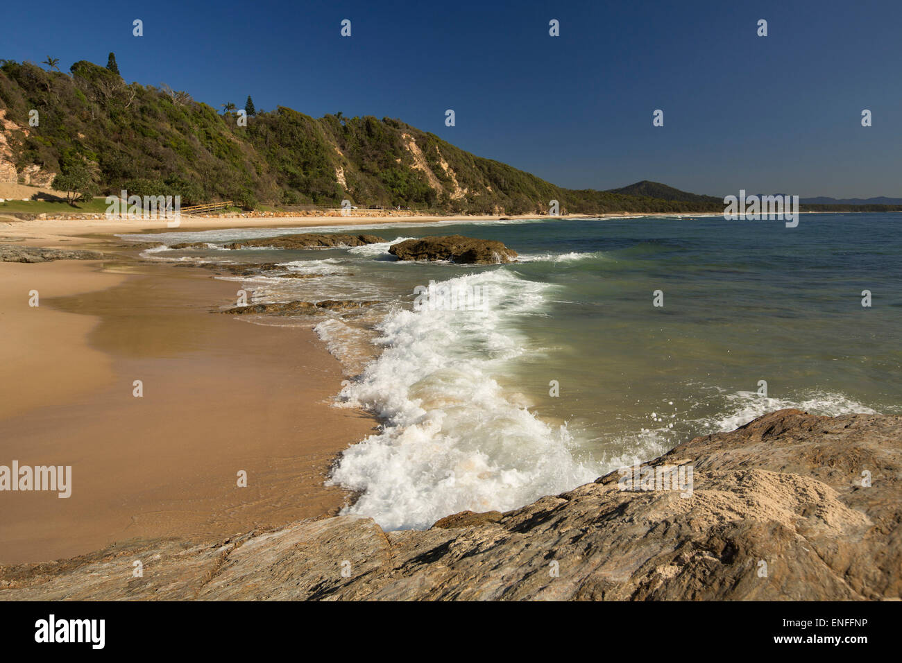 Sandy beach in sheltered bay with blue water and low white capped waves ...