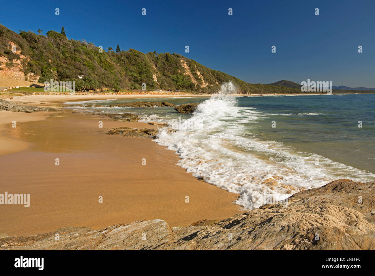 Sandy beach in sheltered bay with blue water and low white capped waves ...