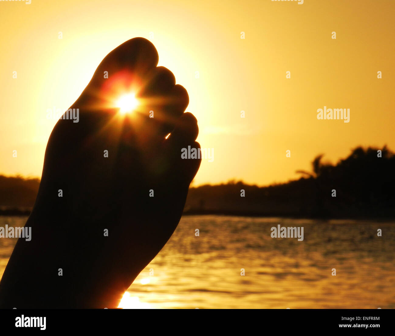 Foot in the sunset, ray of light on a tropical beach Stock Photo - Alamy