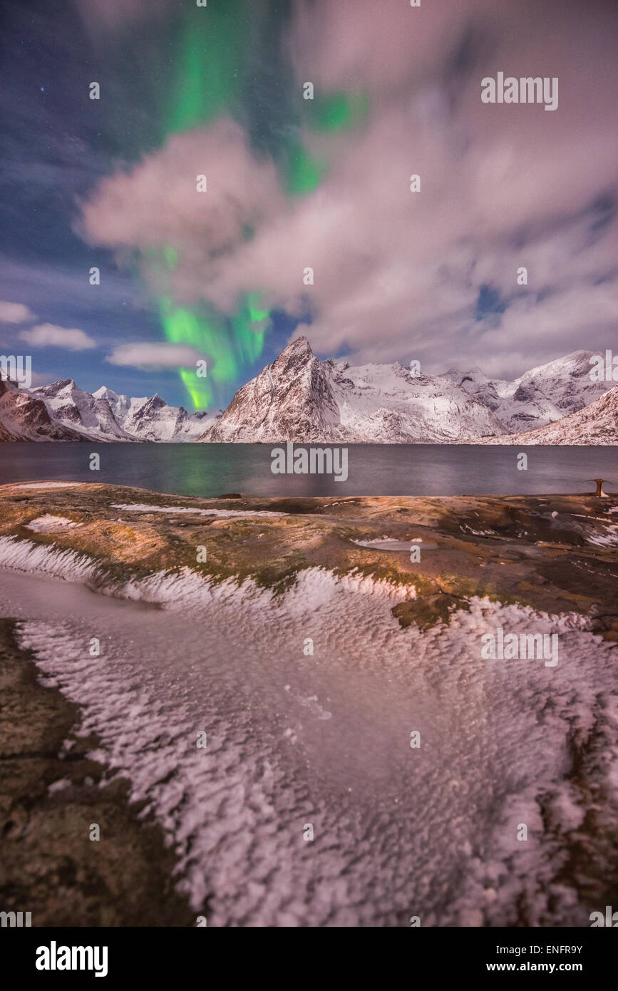 Small aurora with clouds, rocks and ice, mountains at the back, Hamnoy ...