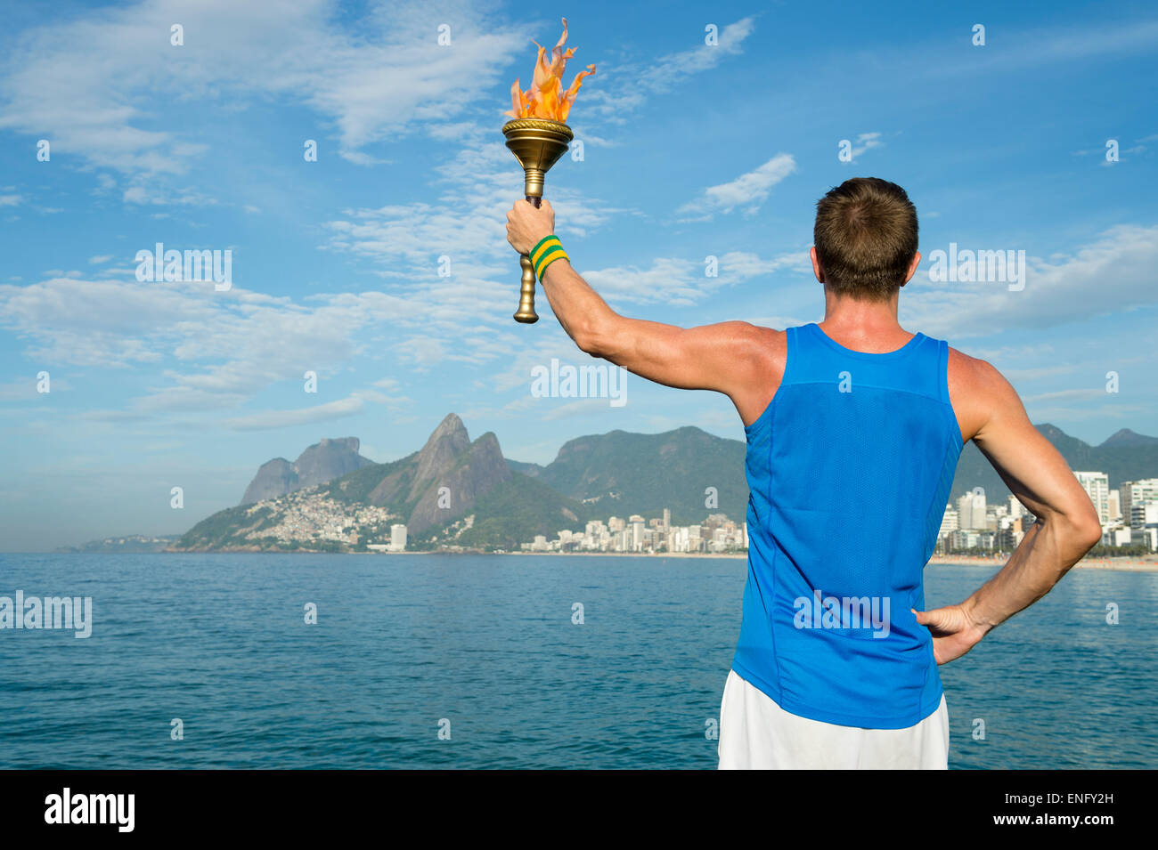 Athlete in in athletic uniform standing with sport torch above Rio de ...