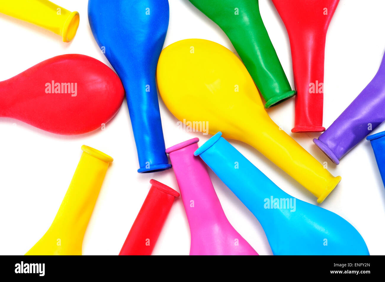 a pile of uninflated balloons of different colors on a white background ...