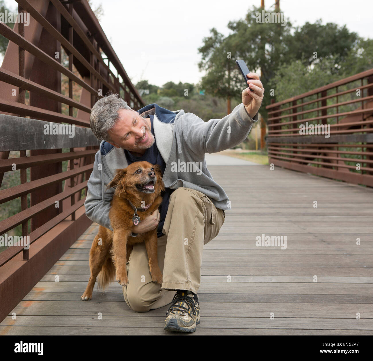 Caucasian man taking photograph with dog on bridge Stock Photo - Alamy