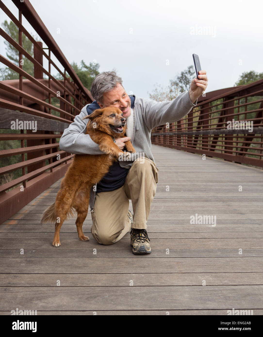 Caucasian man taking photograph with dog on bridge Stock Photo - Alamy