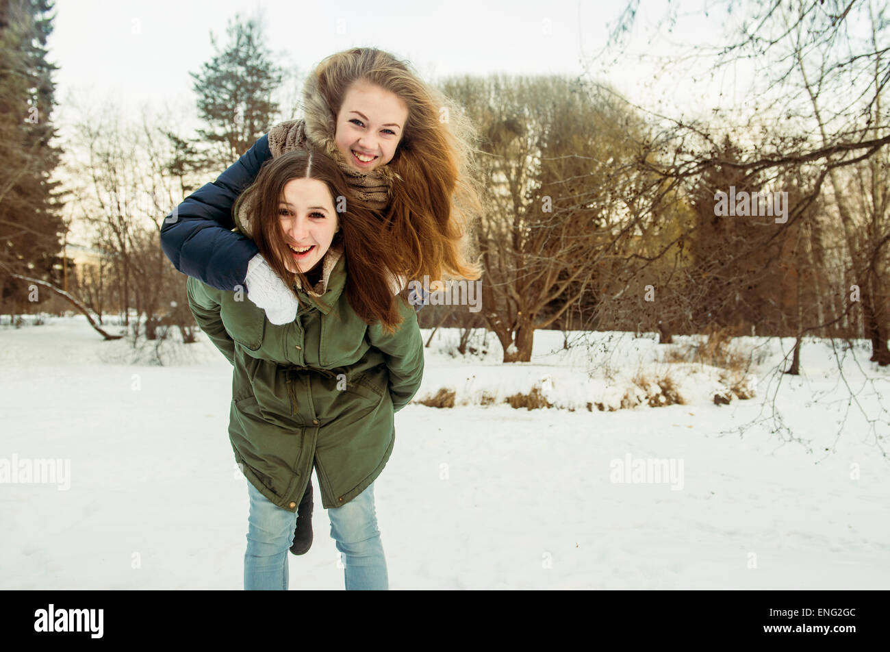 Caucasian woman carrying friend piggyback in snowy field Stock Photo ...