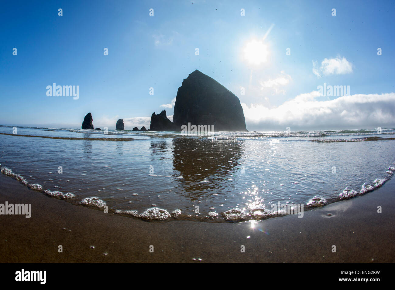 Low angle view of Haystack Rock reflecting in ocean waves, Cannon Beach ...