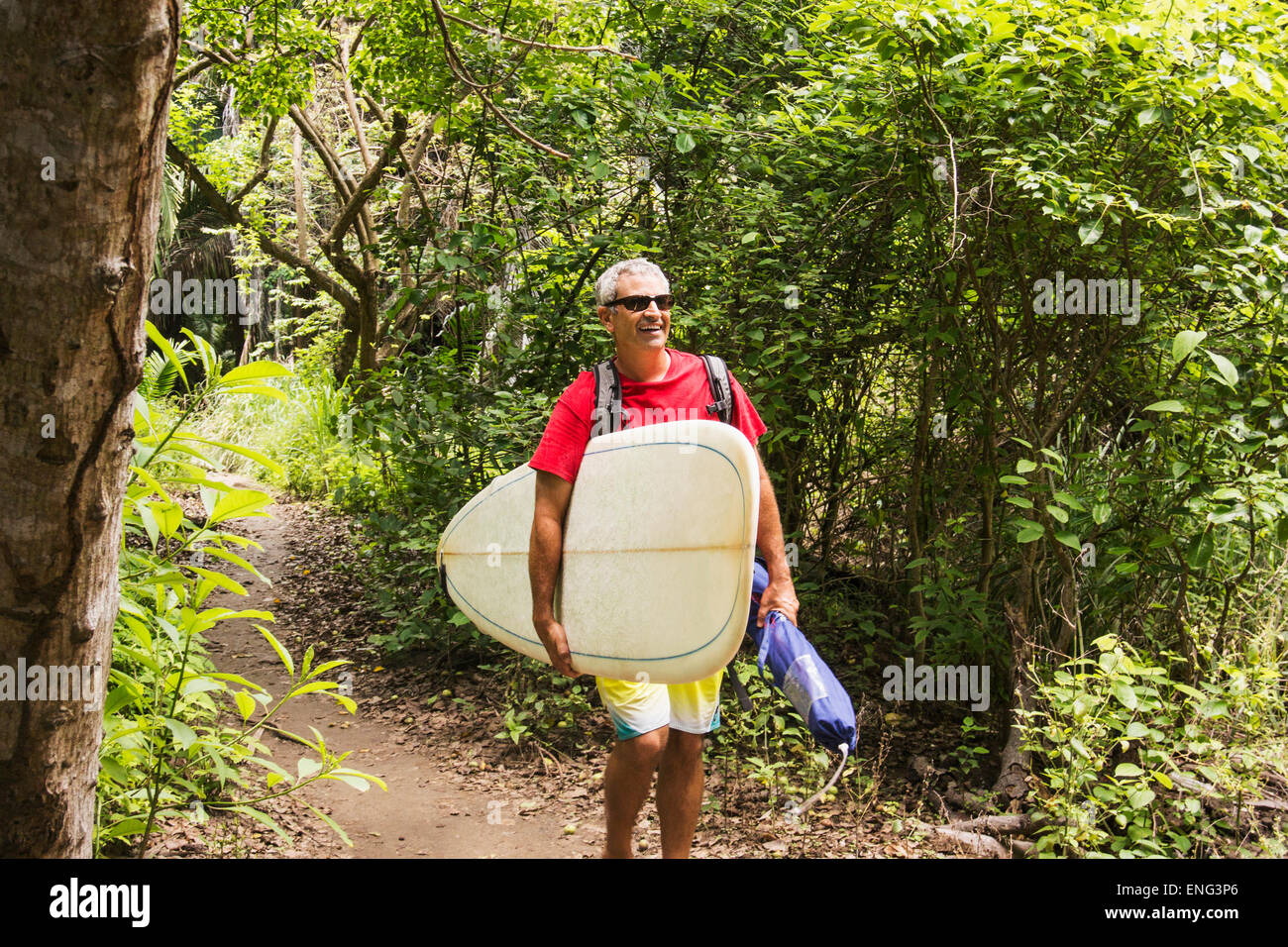 Caucasian man carrying surfboard in jungle Stock Photo - Alamy