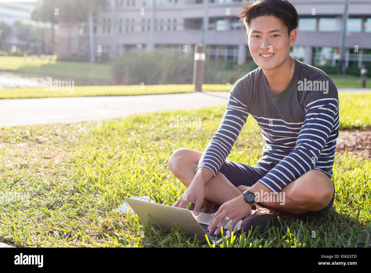 Korean man using laptop in grass Stock Photo - Alamy