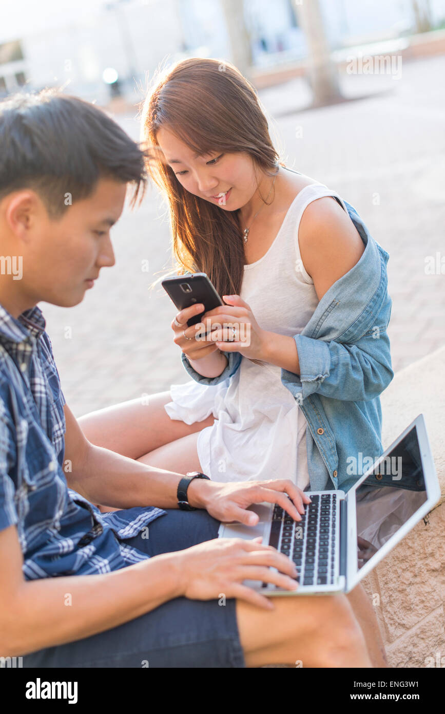 Korean couple using laptop and cell phone outdoors Stock Photo - Alamy