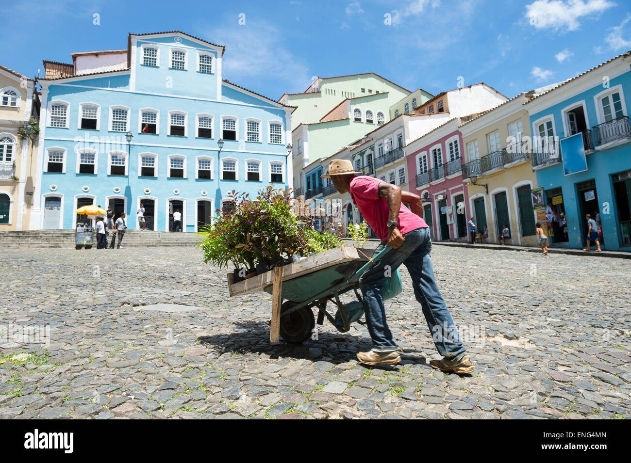 Brazilian vendor pushes wheelbarrow full of greenery up a cobblestone ...