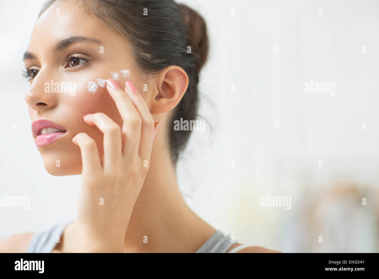 Woman applying moisturizer to cheek Stock Photo - Alamy