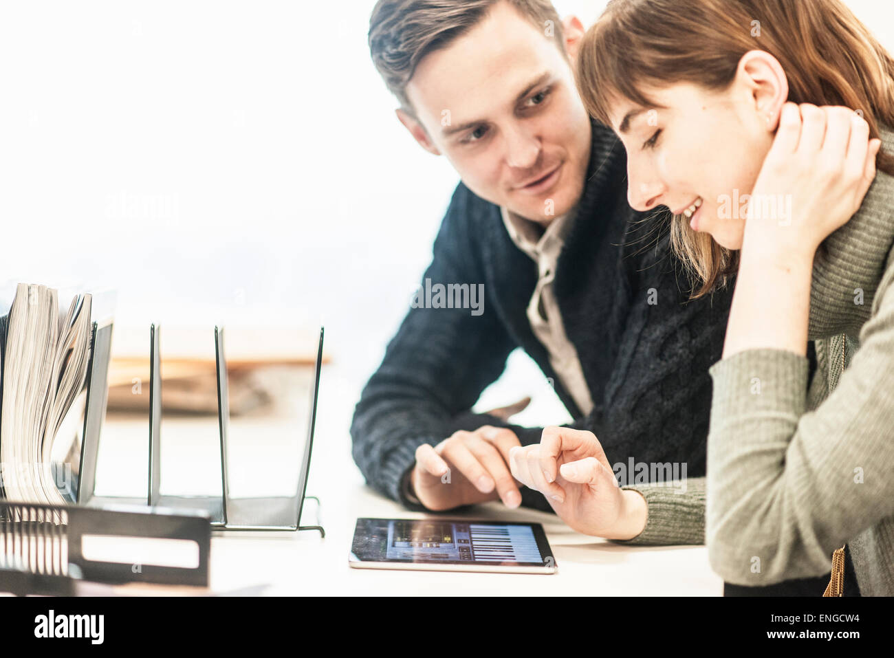A man and a woman seated side by side talking at a desk in an office ...