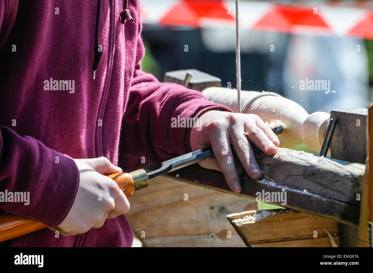 Young man uses a wood chisel and a foot operated lathe to turn wood ...